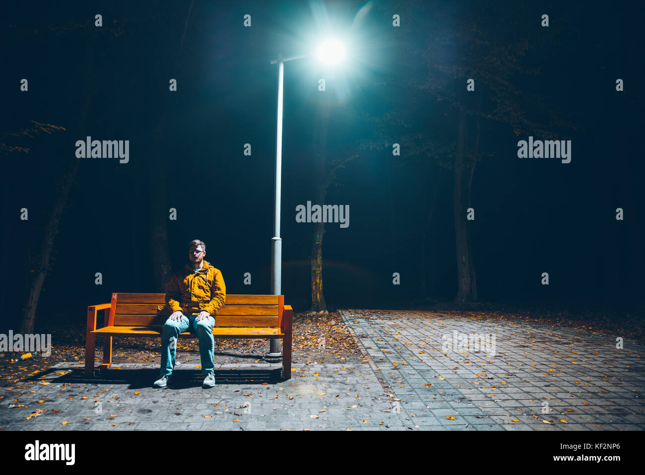 lonely man sitting in night park under the light Stock Photo - Alamy