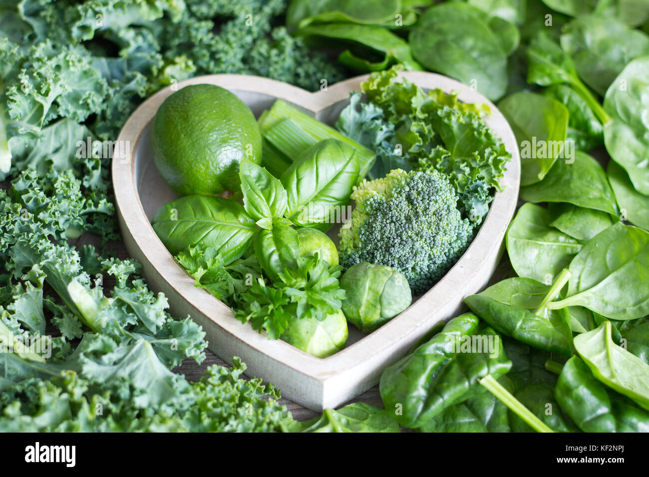 Green vegetables and herbs in heart health concept Stock Photo - Alamy