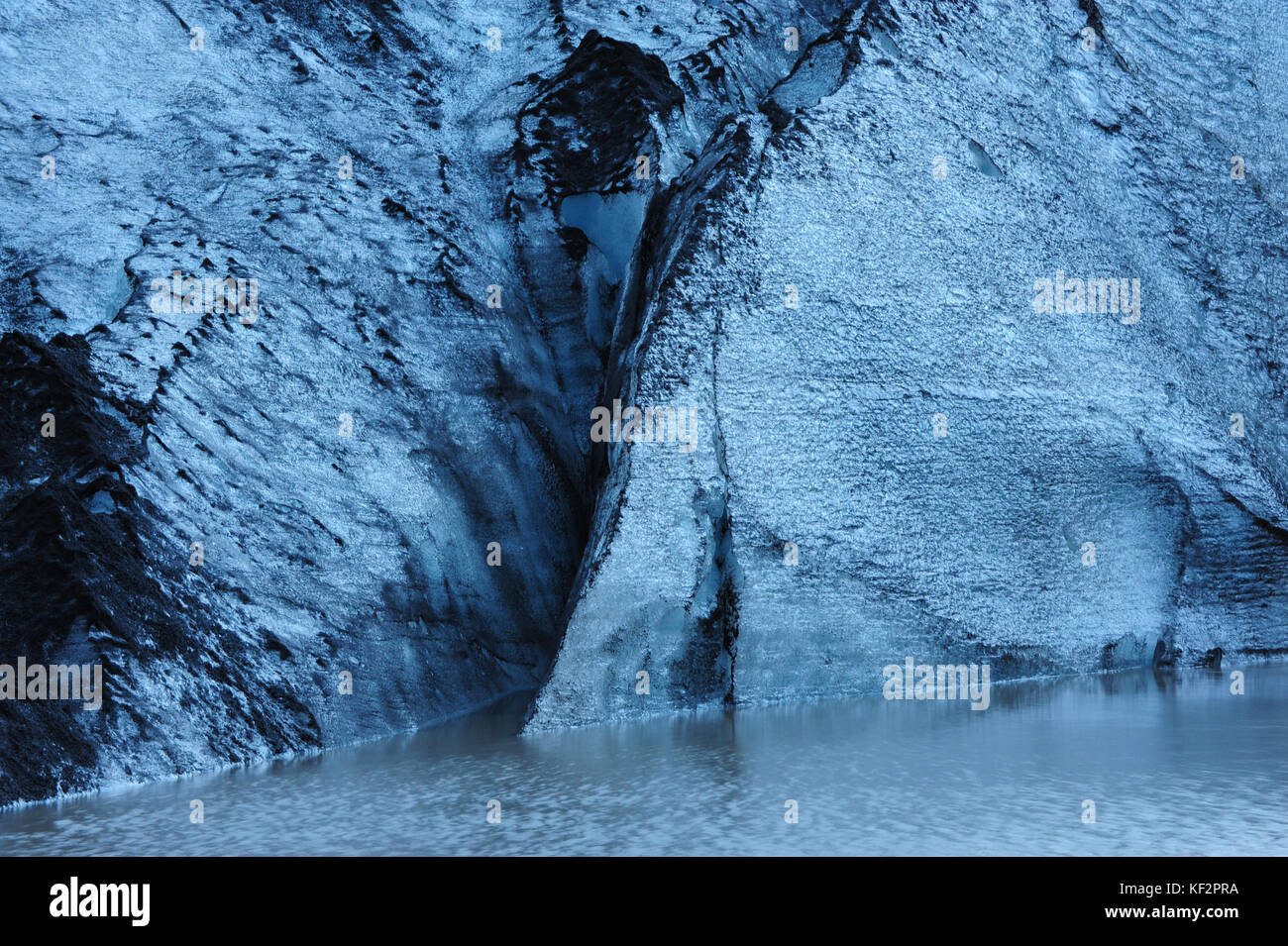 Details of sapphire blue ice glacier close up cracks with black silt ...