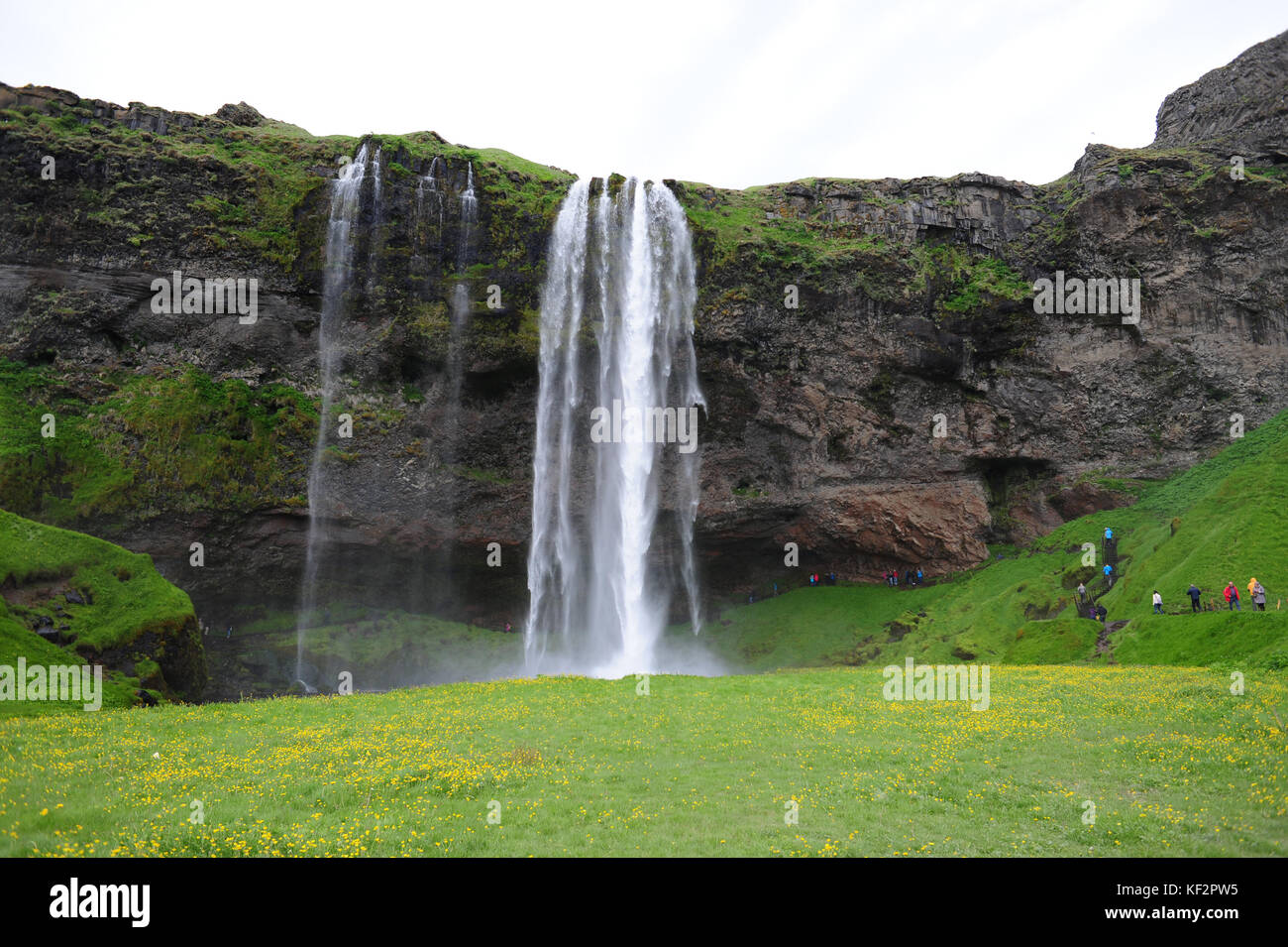 Many tourists walking along path beside and behind Seljalandsfoss ...