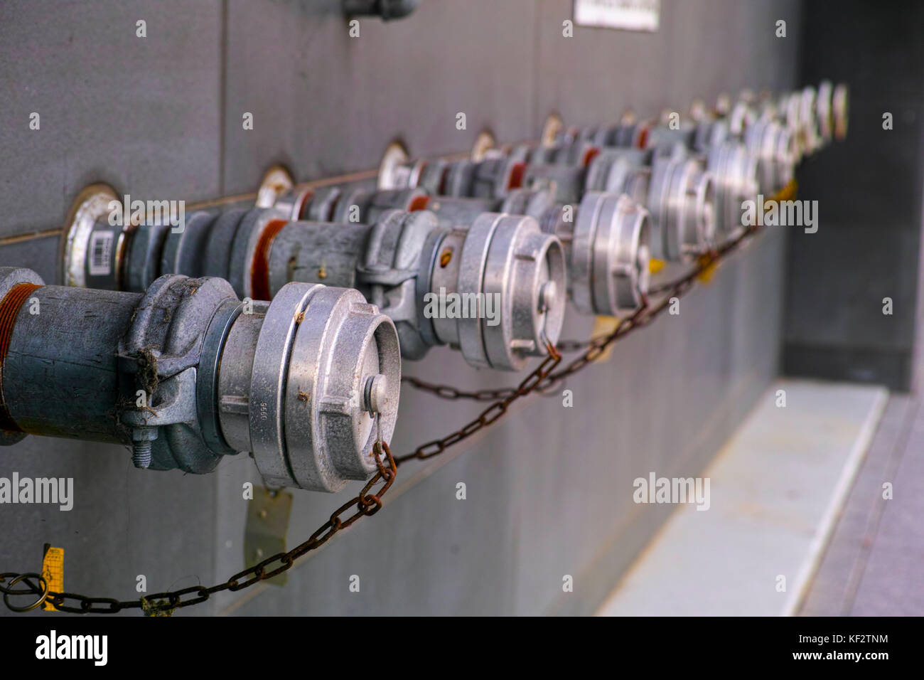 Row of metallic fire hydrants linked with a chain on building wall on a ...