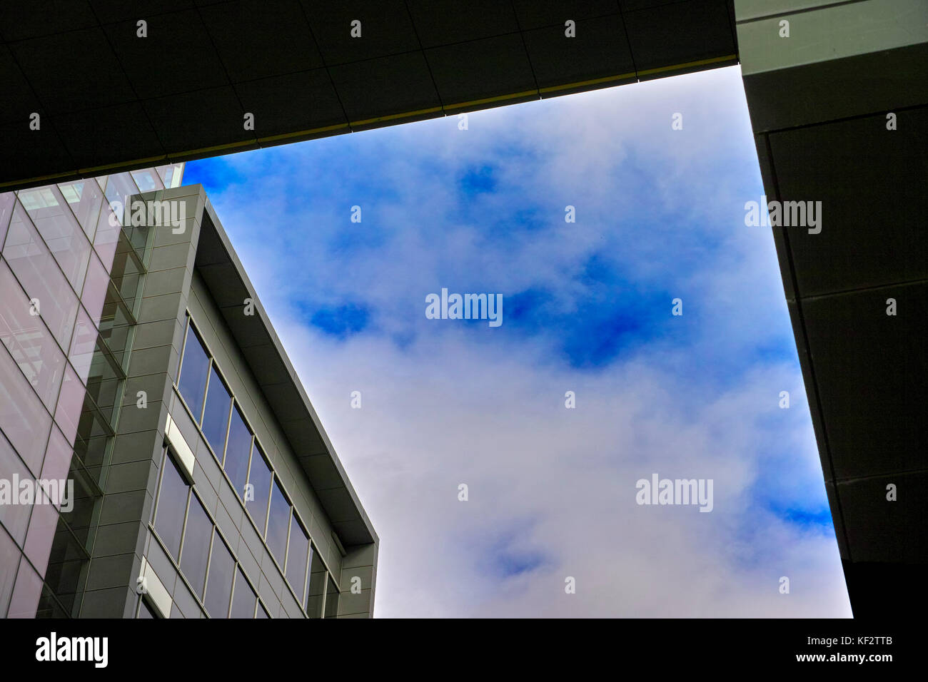 Sky with clouds visible between office buildings. Looking up at tall ...