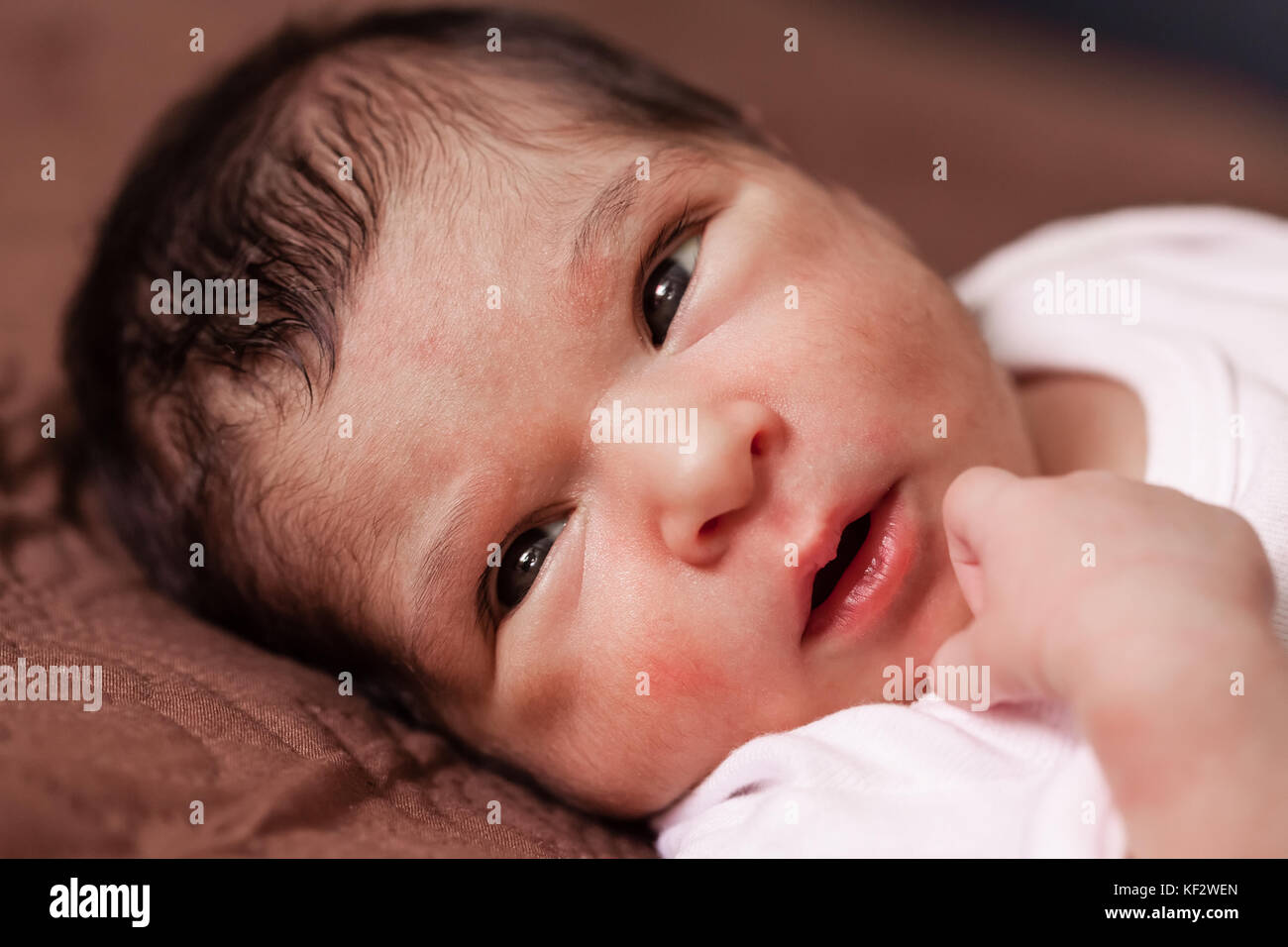 Close up portrait of a cute two weeks old newborn baby girl lying down ...
