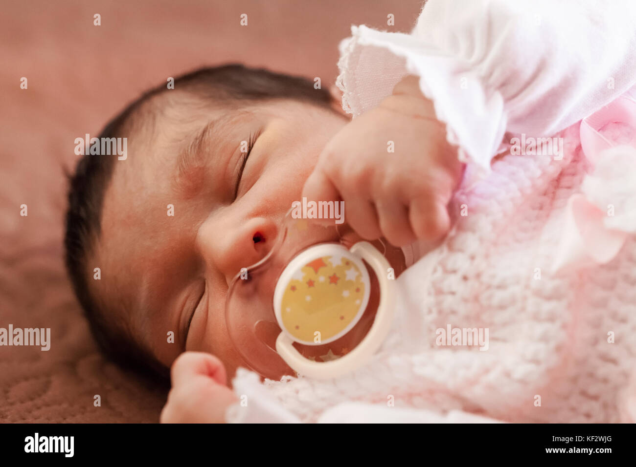 Close up portrait of a cute two weeks old newborn baby girl wearing ...