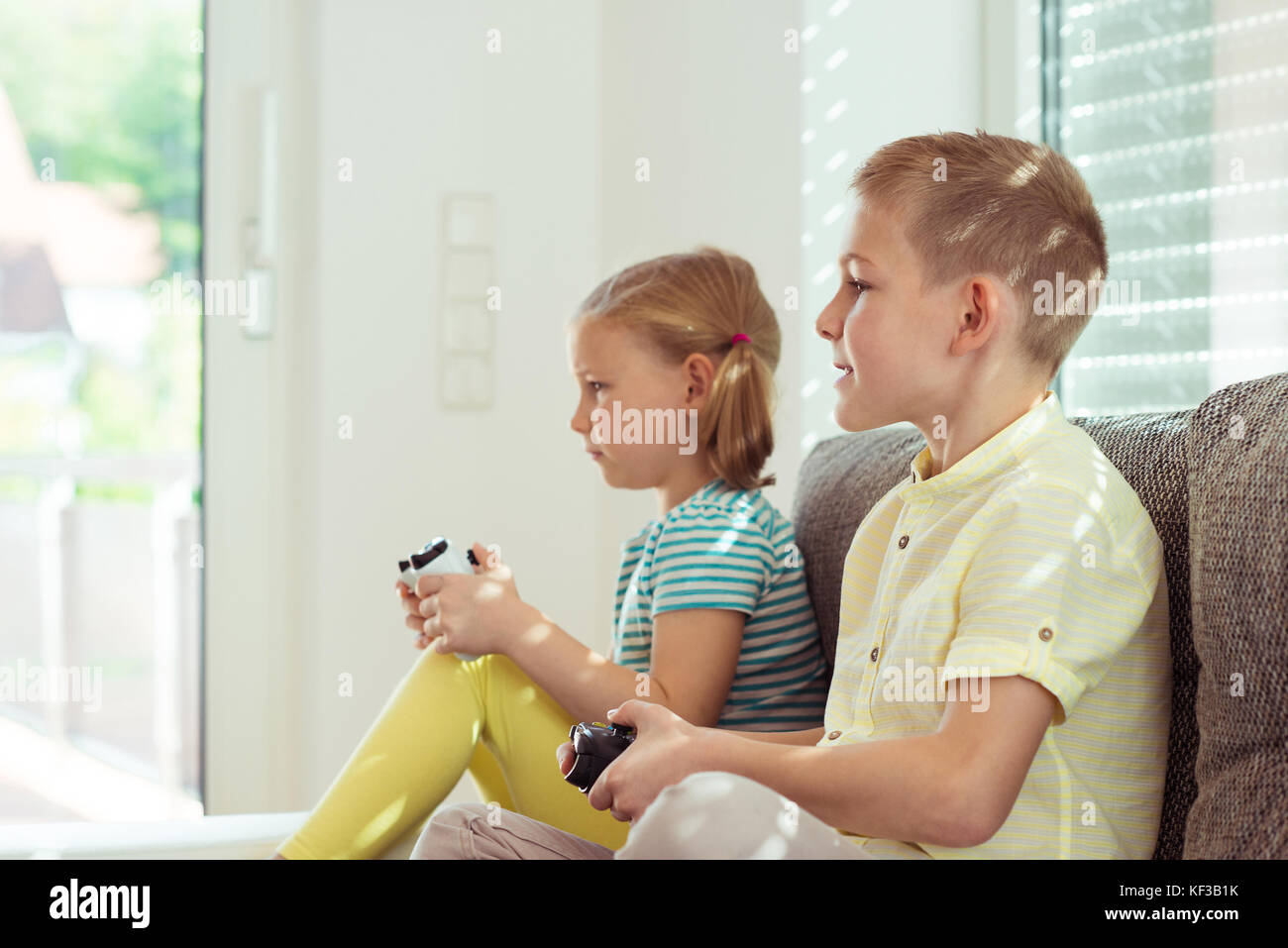 Two happy children playing video games with console at home Stock Photo ...