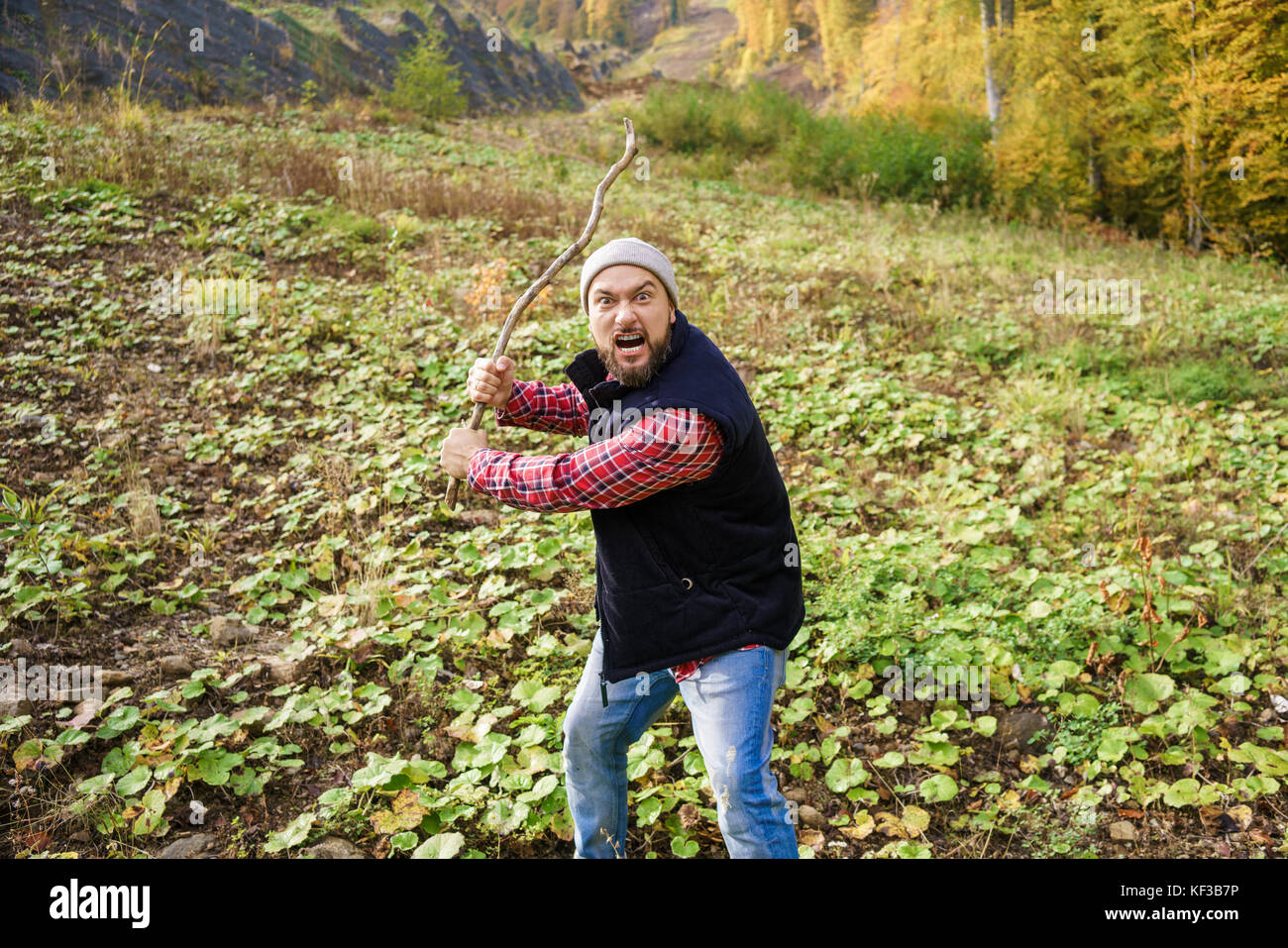aggressive man with a stick in a hand Stock Photo - Alamy