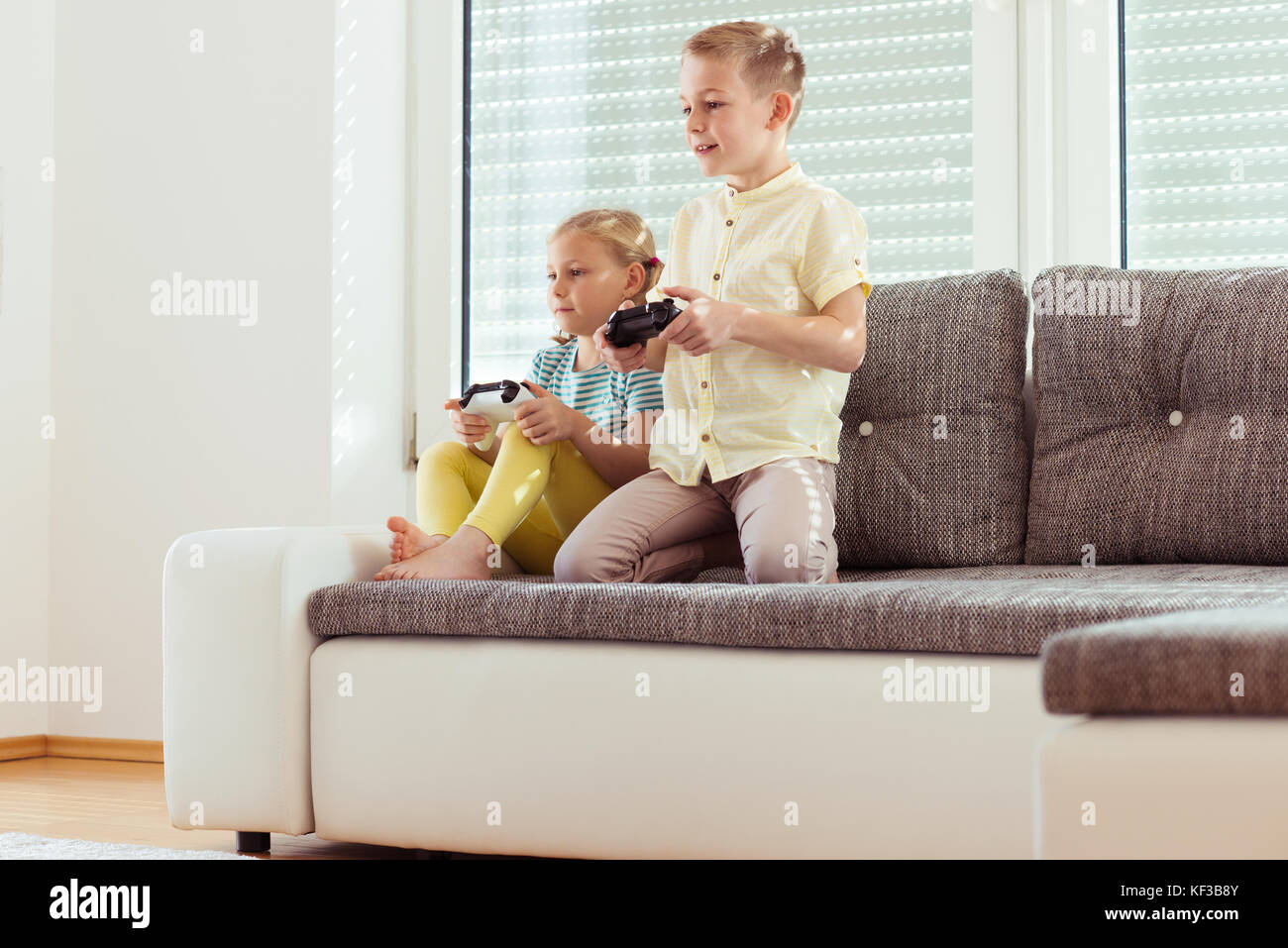 Two happy children playing video games with console at home Stock Photo ...