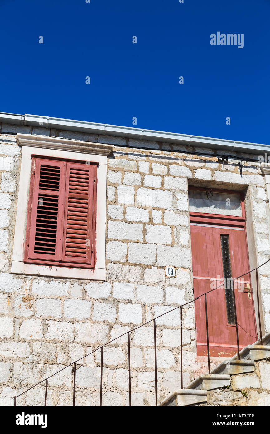 A first floor apartment decorated with red wooden shutters and a door ...