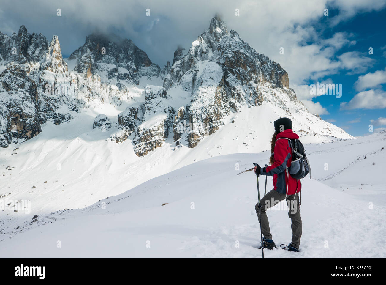 Young woman explorer looking at the mountain range in winter scenery ...