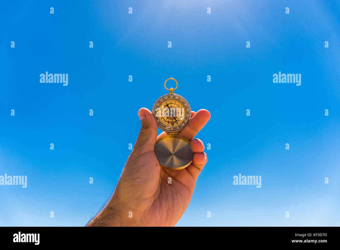 Hand holding a compass with blue sky background Stock Photo - Alamy