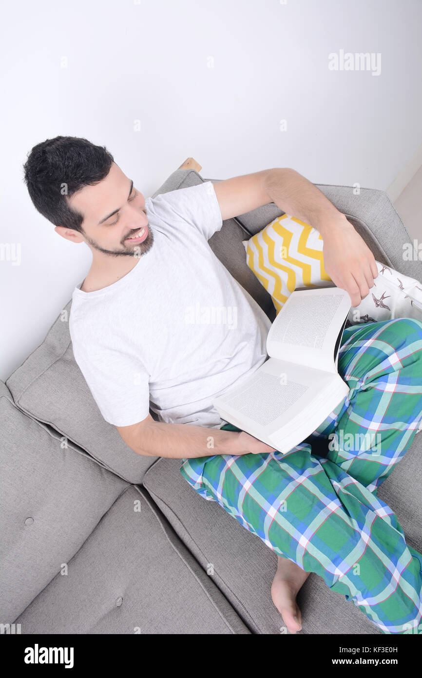Attractive young man relaxed and reading a book. Indoors Stock Photo ...