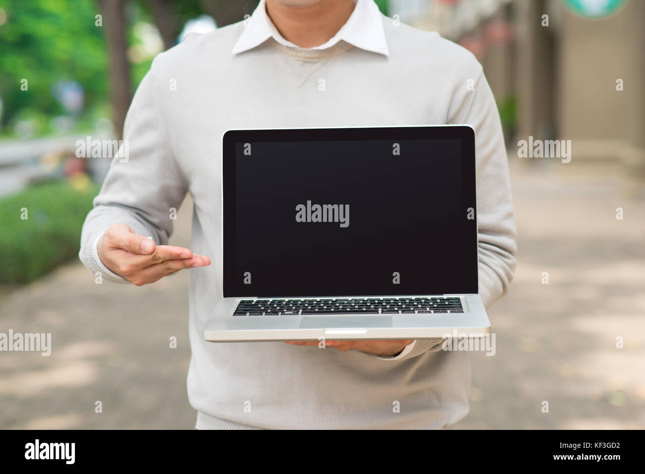 Young business man holding and showing the screen of laptop Stock Photo ...