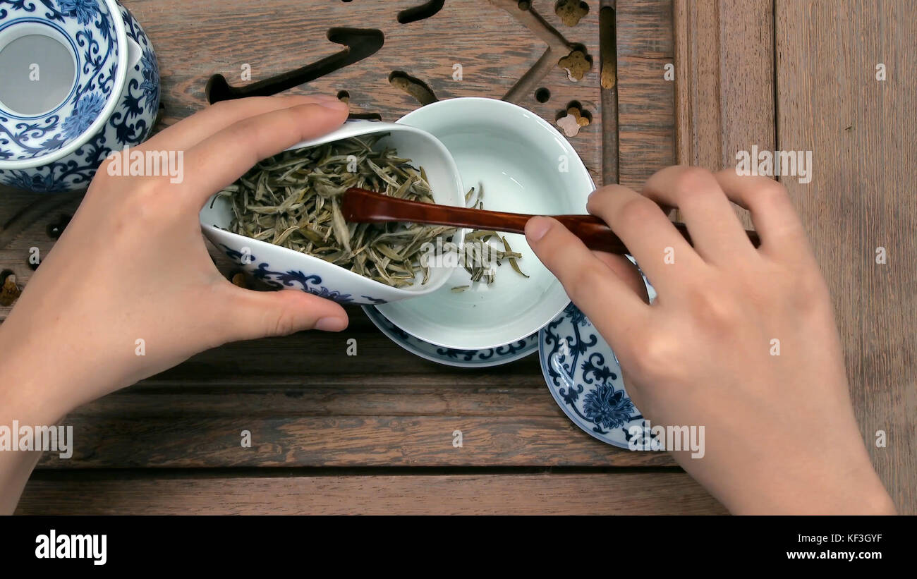 Filling a brown teapot through a funnel. Porcelain chinese cups, steel ...
