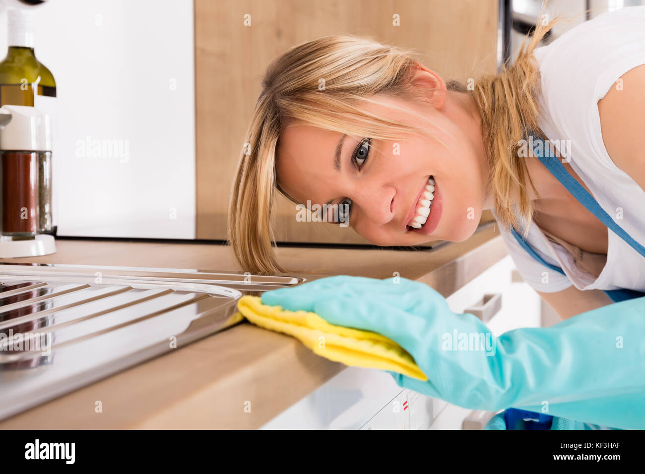 Close-up Of Smiling Young Janitor Woman Cleaning Dirty Kitchen Worktop ...