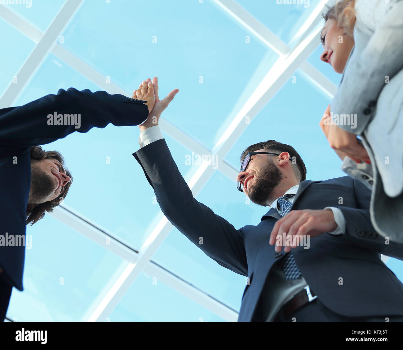 Happy business team giving high five in office Stock Photo - Alamy
