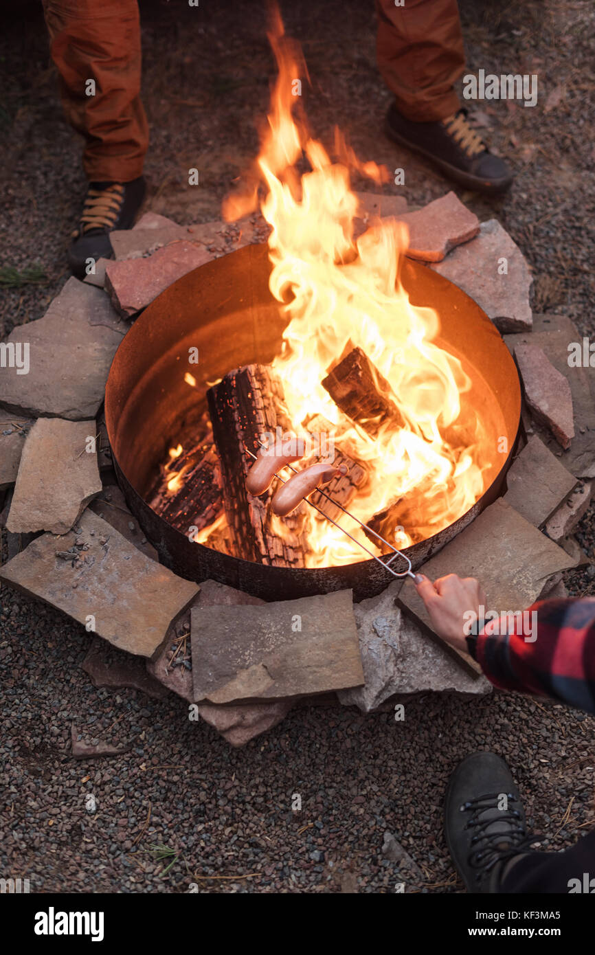 Grilling sausages over a campfire, campers roasting sausages on ...