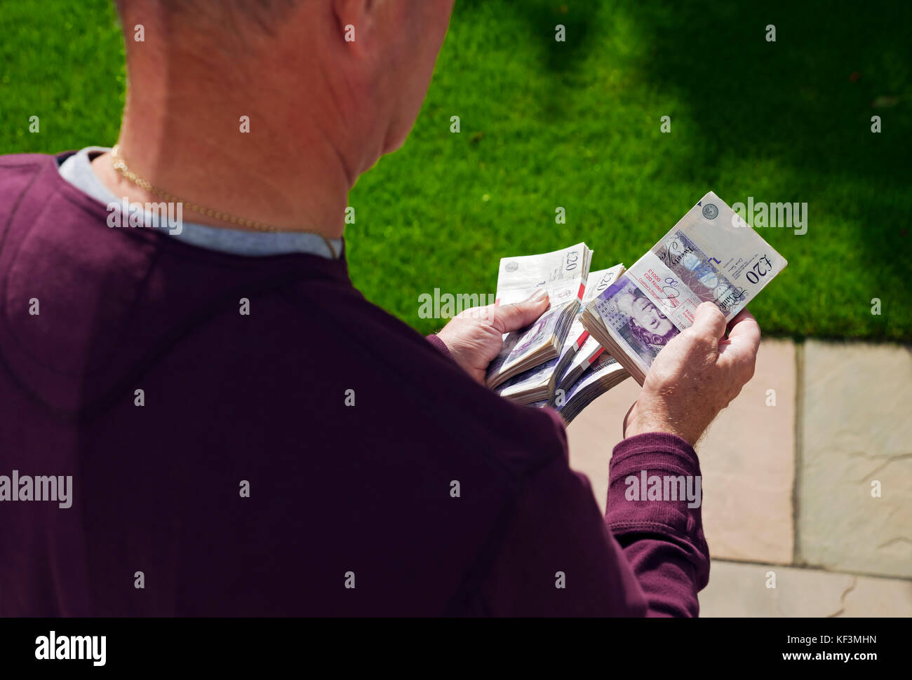Close up of man person holding bundles of English money £20 twenty ...