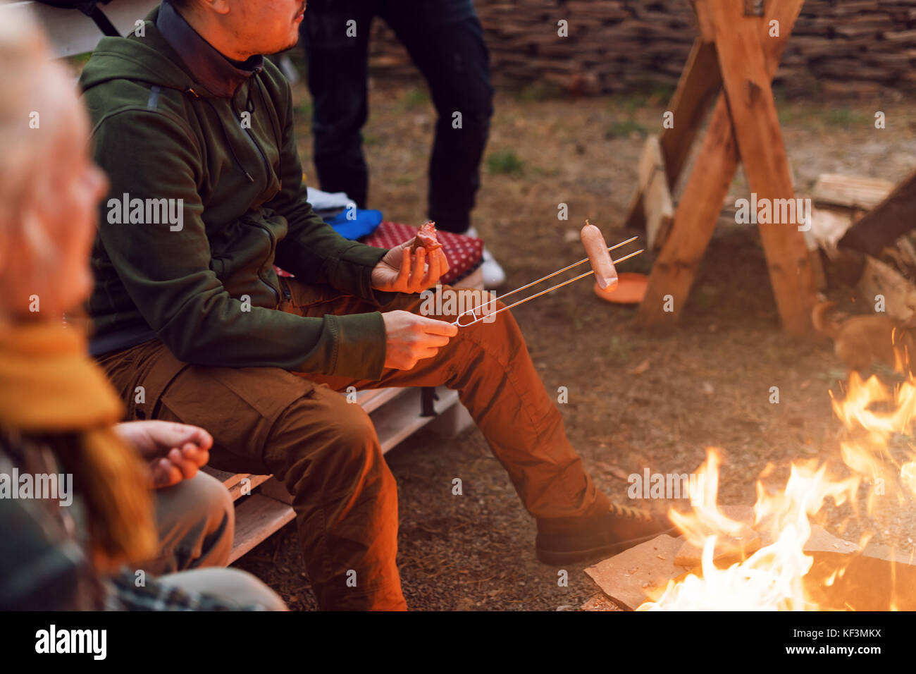 Grilling sausages over a campfire, campers roasting sausages on ...