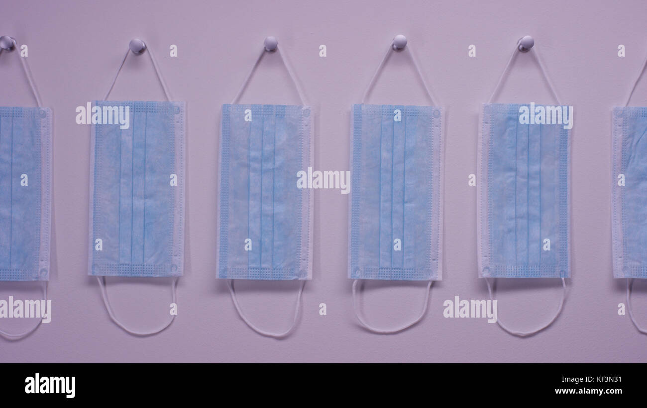 Hand takes protective mask from wall. Surgical Ear-Loop Masks on white ...