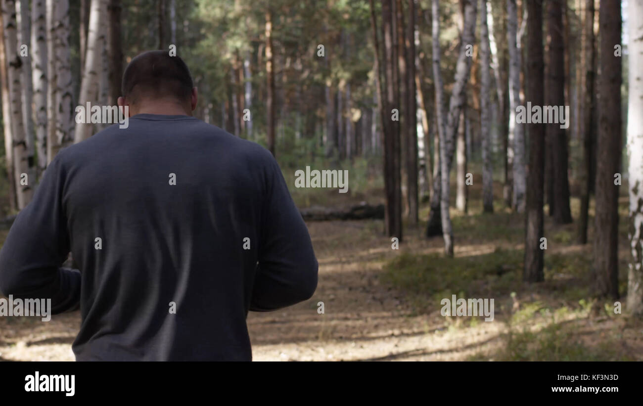 Muscular runner running on road through forest. Back view. Athletic man ...