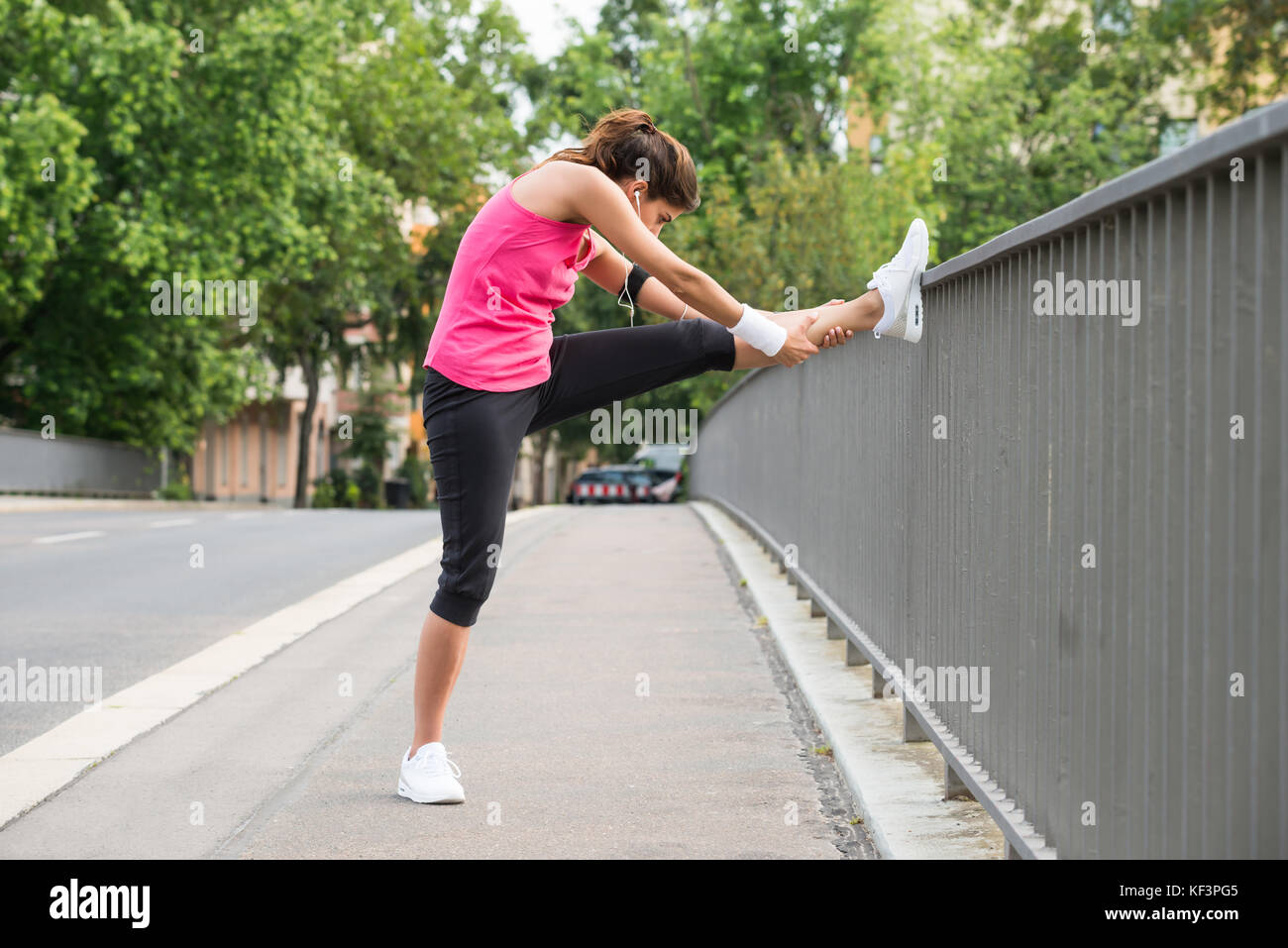 Young Woman Stretching Her Legs Over Fence At Road Stock Photo - Alamy