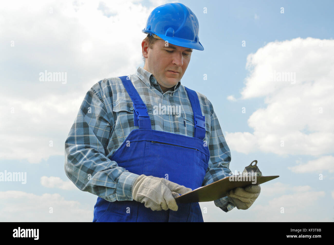 Construction site manager wearing blue helmet and overall with notepad ...