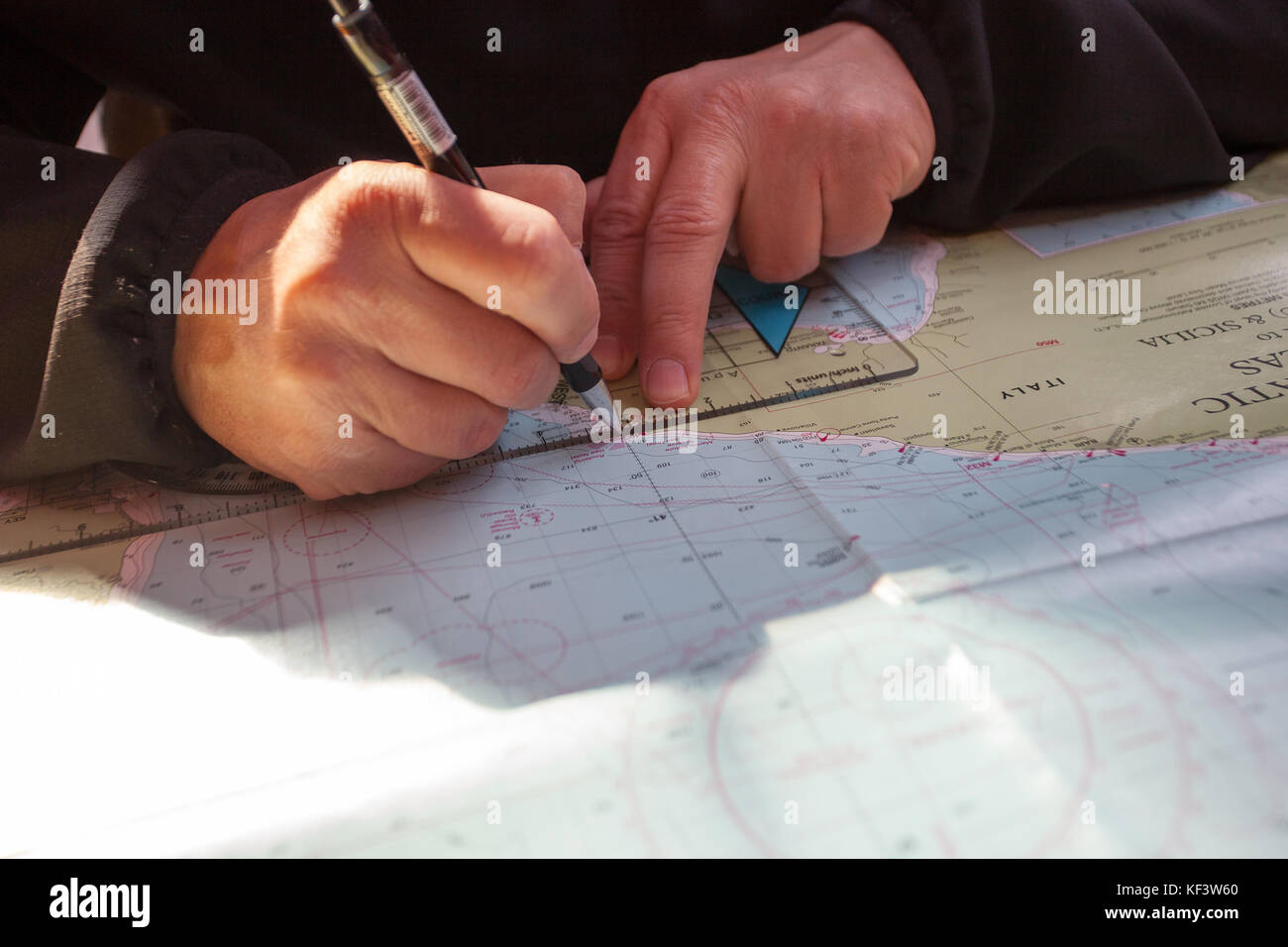 The ship's captain plans the route on the map with a ruler and plotter ...