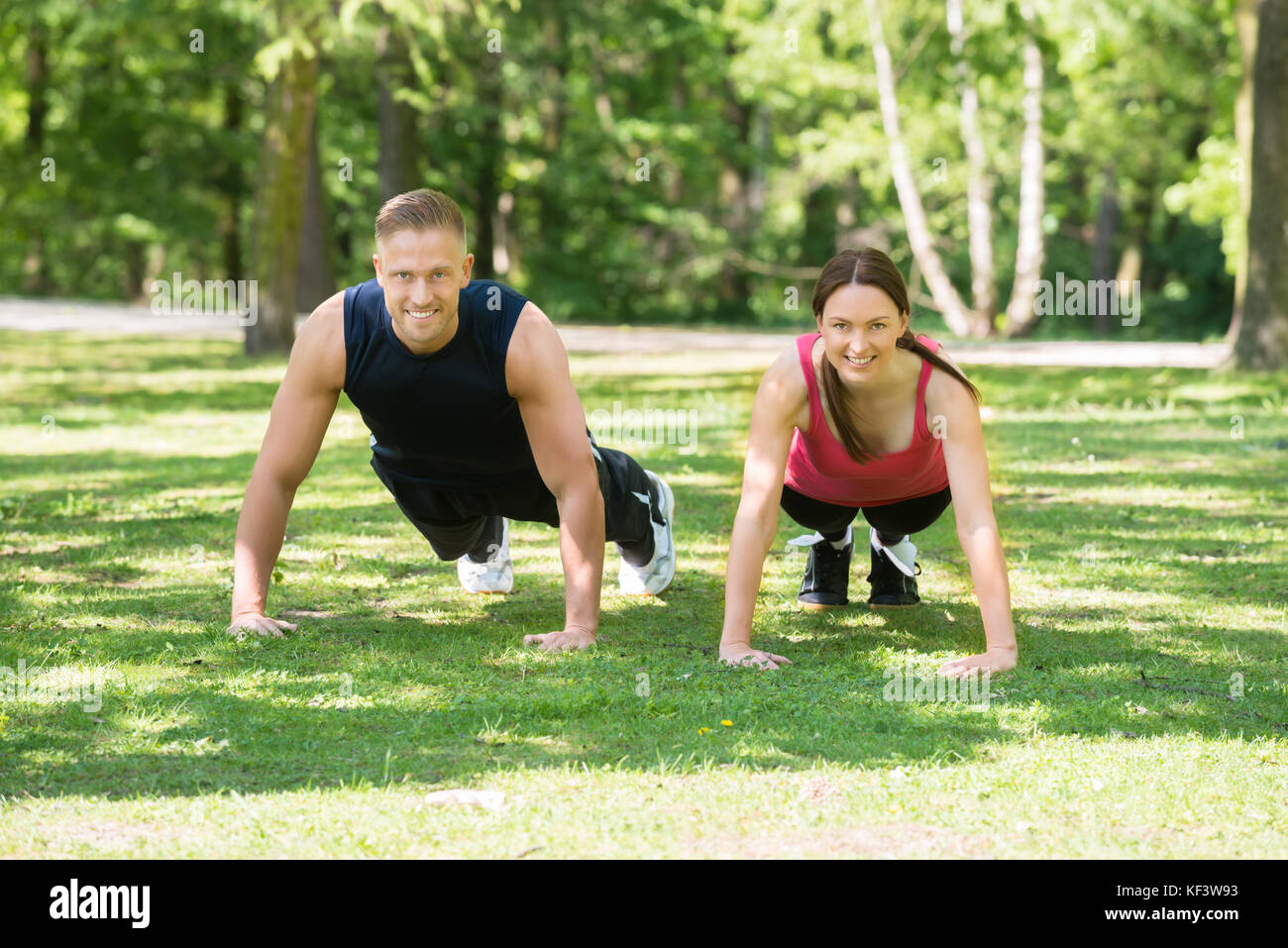 Young Happy Athletic Couple Doing Push-ups In Park Stock Photo - Alamy