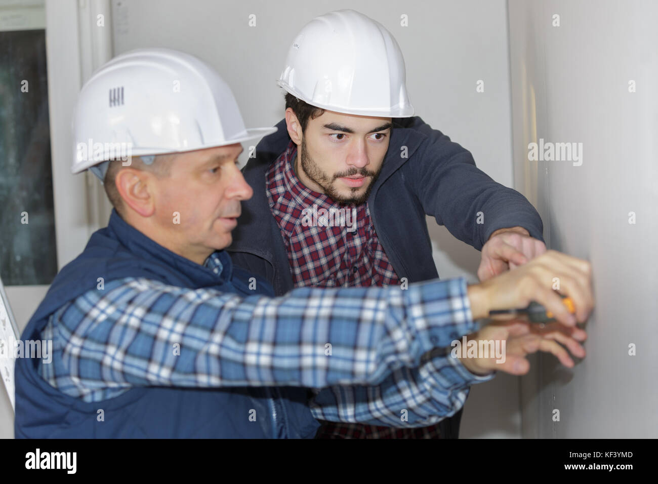 two workmen measureing wall Stock Photo - Alamy