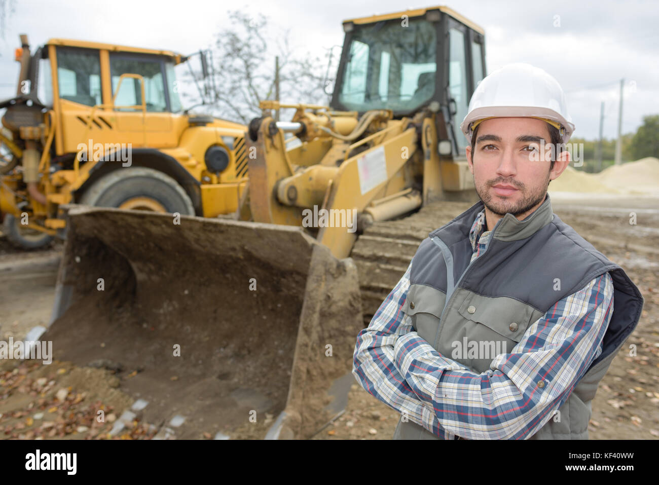 Portrait of construction worker next to digger Stock Photo - Alamy