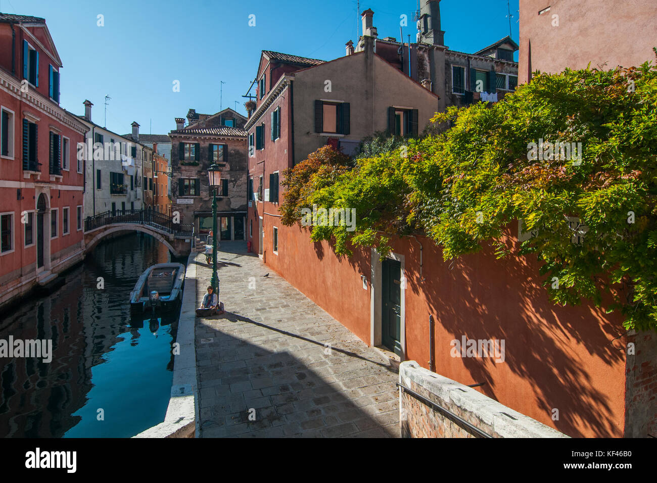 Venice, Italy. October, 2017. A street along a canal trees and plants ...