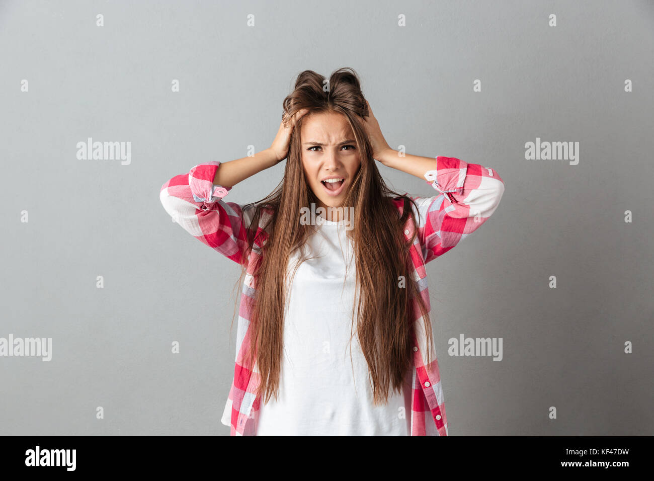 Stressed young woman in rage touching head and screaming with open ...