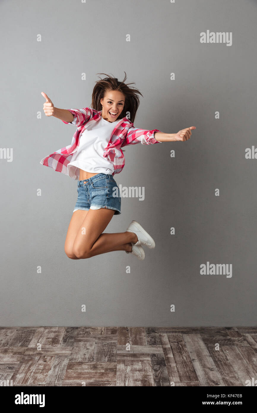 Full-length portrait of pretty jumping girl in casual wear, showing ...