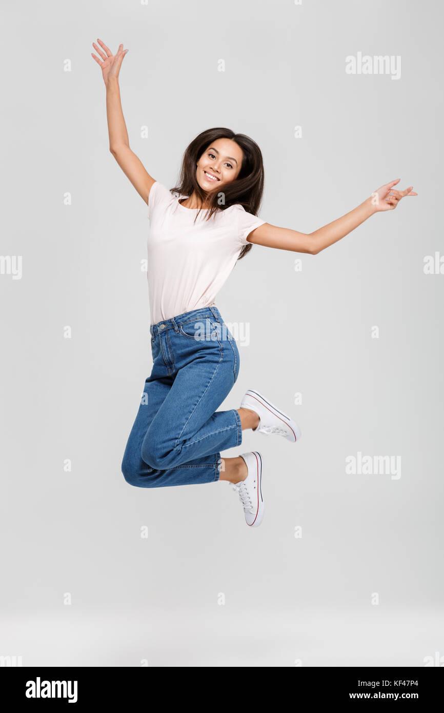 Full length portrait of a happy smiling asian woman jumping with hands ...