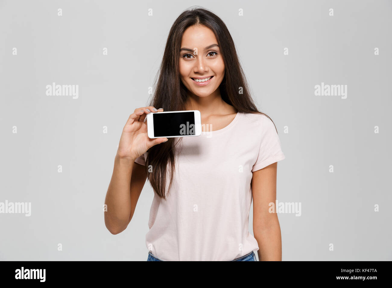 Portrait of a smiling pretty asian woman showing blank screen mobile ...