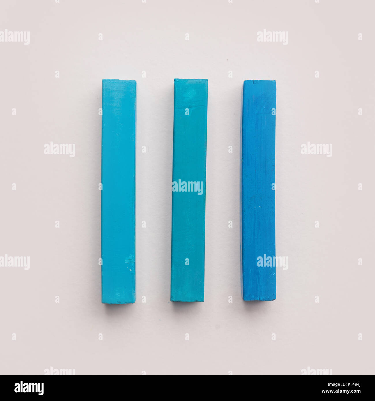 Three pieces of blue pastel crayon chalks isolated over white ...