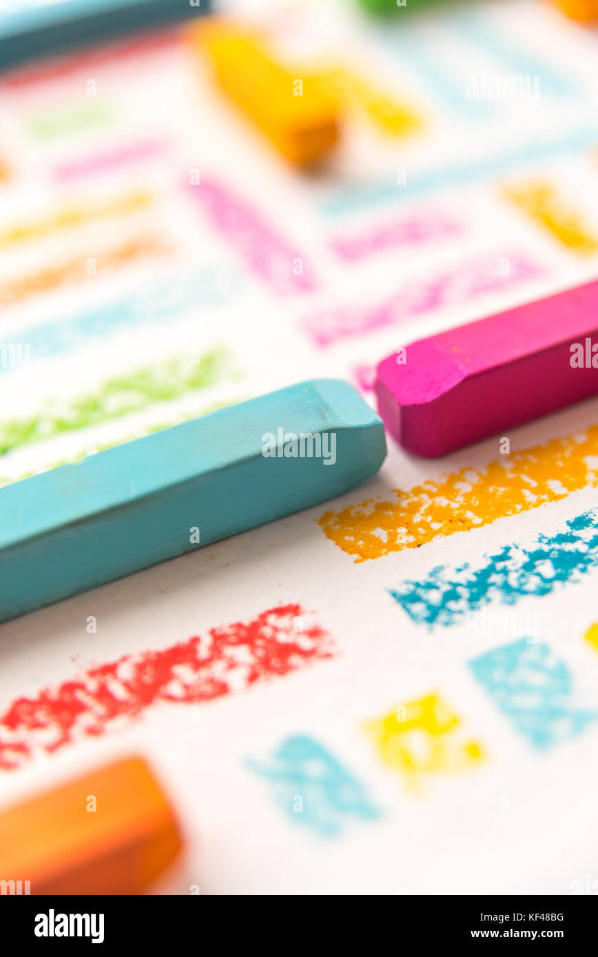 Cropped photo of pieces of chalk, over abstract colorful background ...