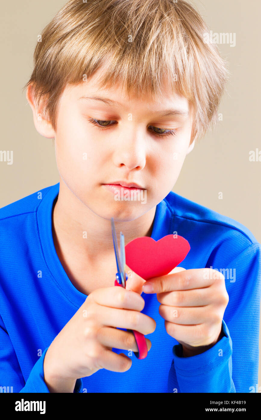 Boy cutting red paper heart with scissors Stock Photo - Alamy