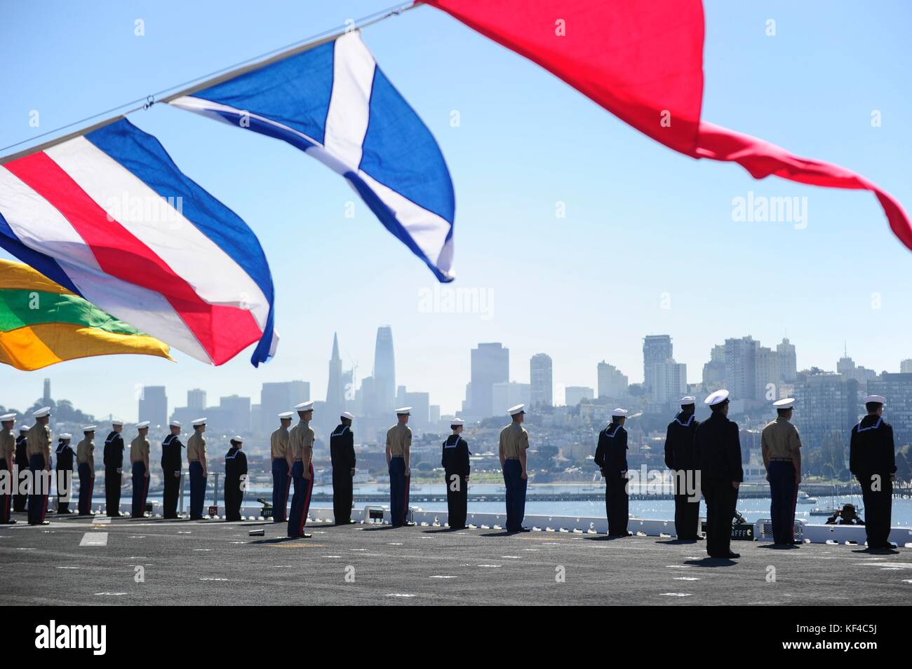 U.S. Navy sailors and U.S. Marines man the rails on the flight deck ...