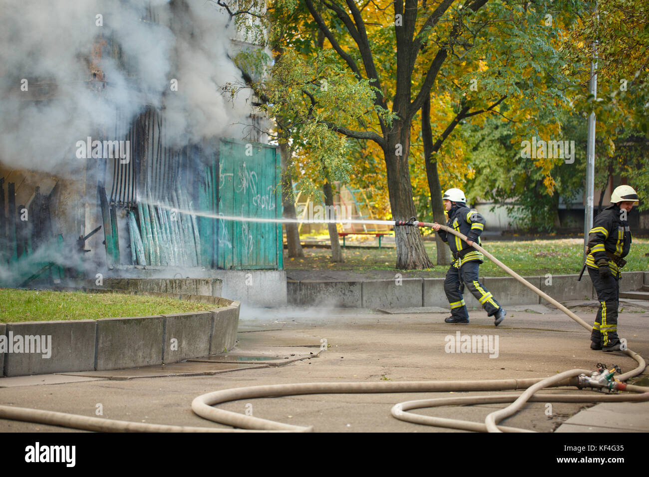 two firefighters with protective uniform and helmet off the fire ...