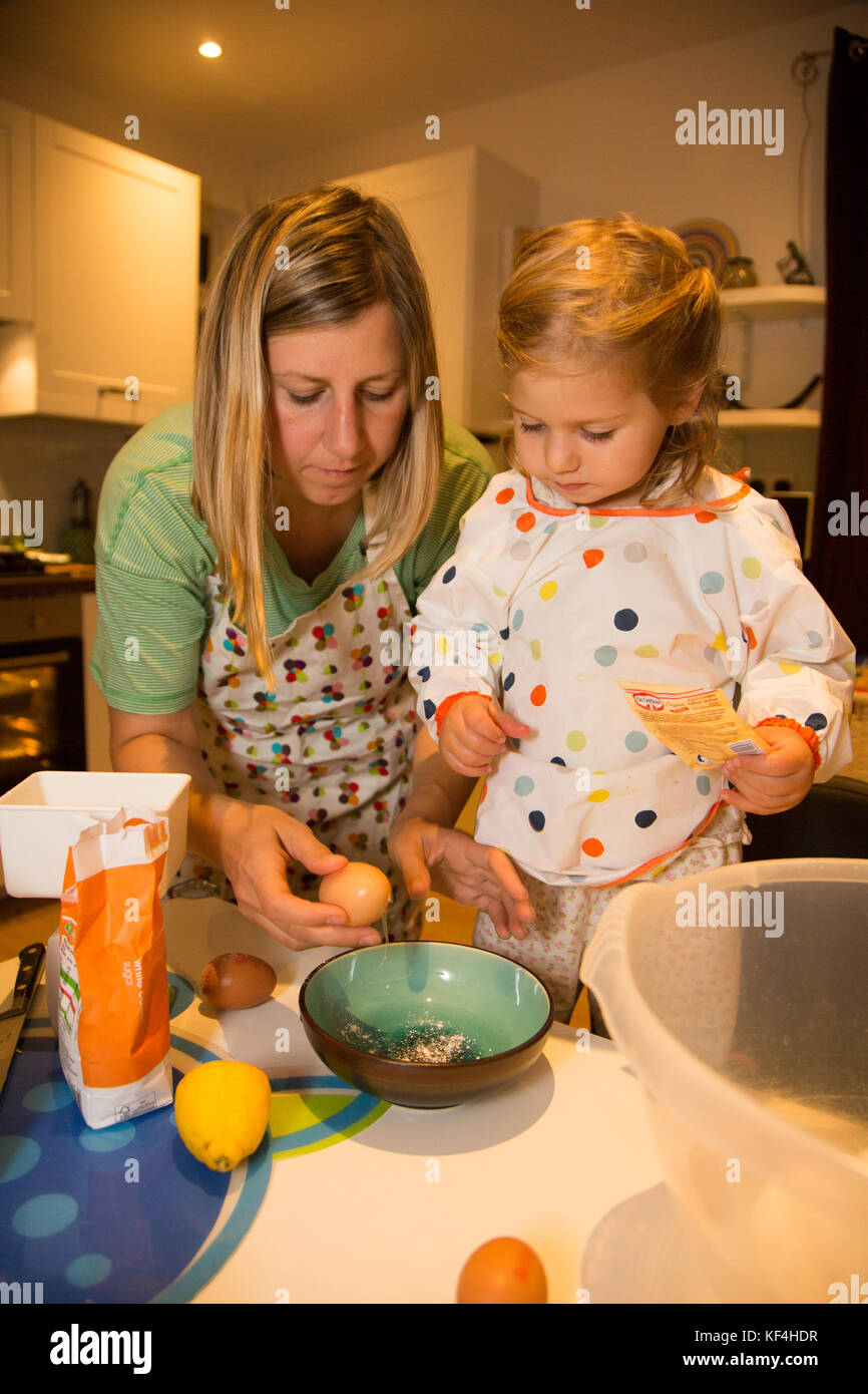 Mother and daughter mixing ingredients in preparation for baking a cake ...