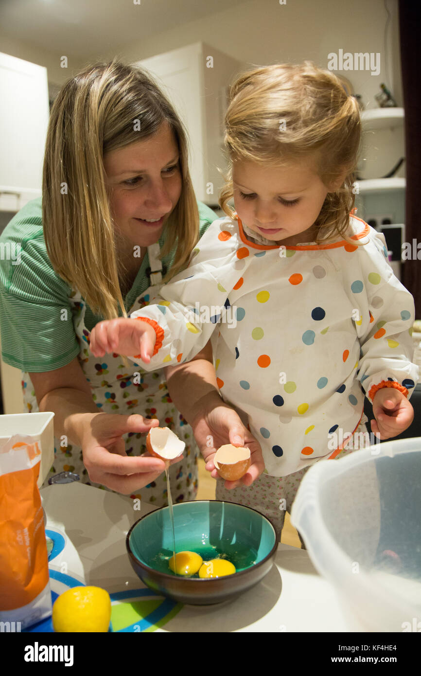 Mother and daughter mixing ingredients in preparation for baking a cake ...