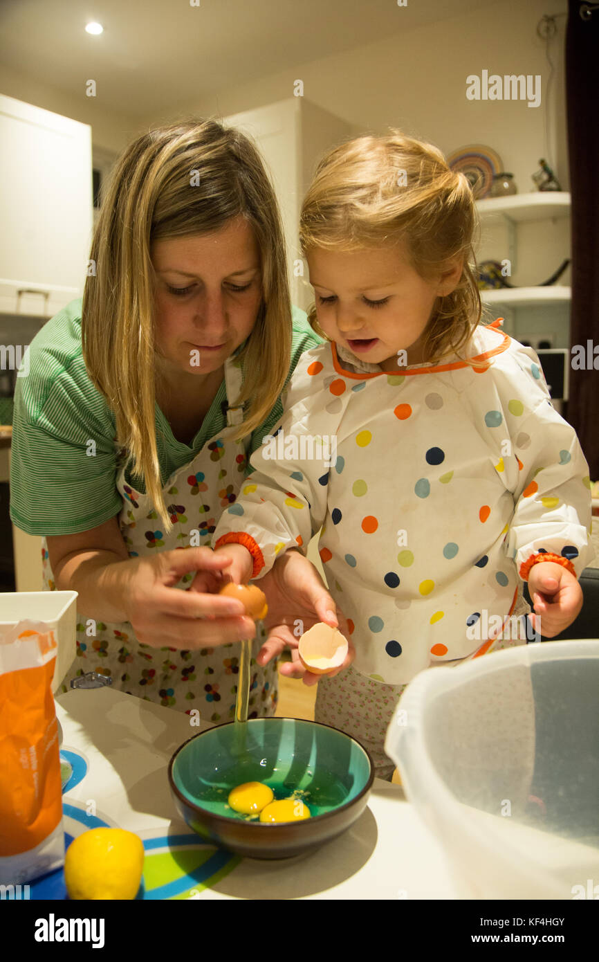 Mother and daughter mixing ingredients in preparation for baking a cake ...
