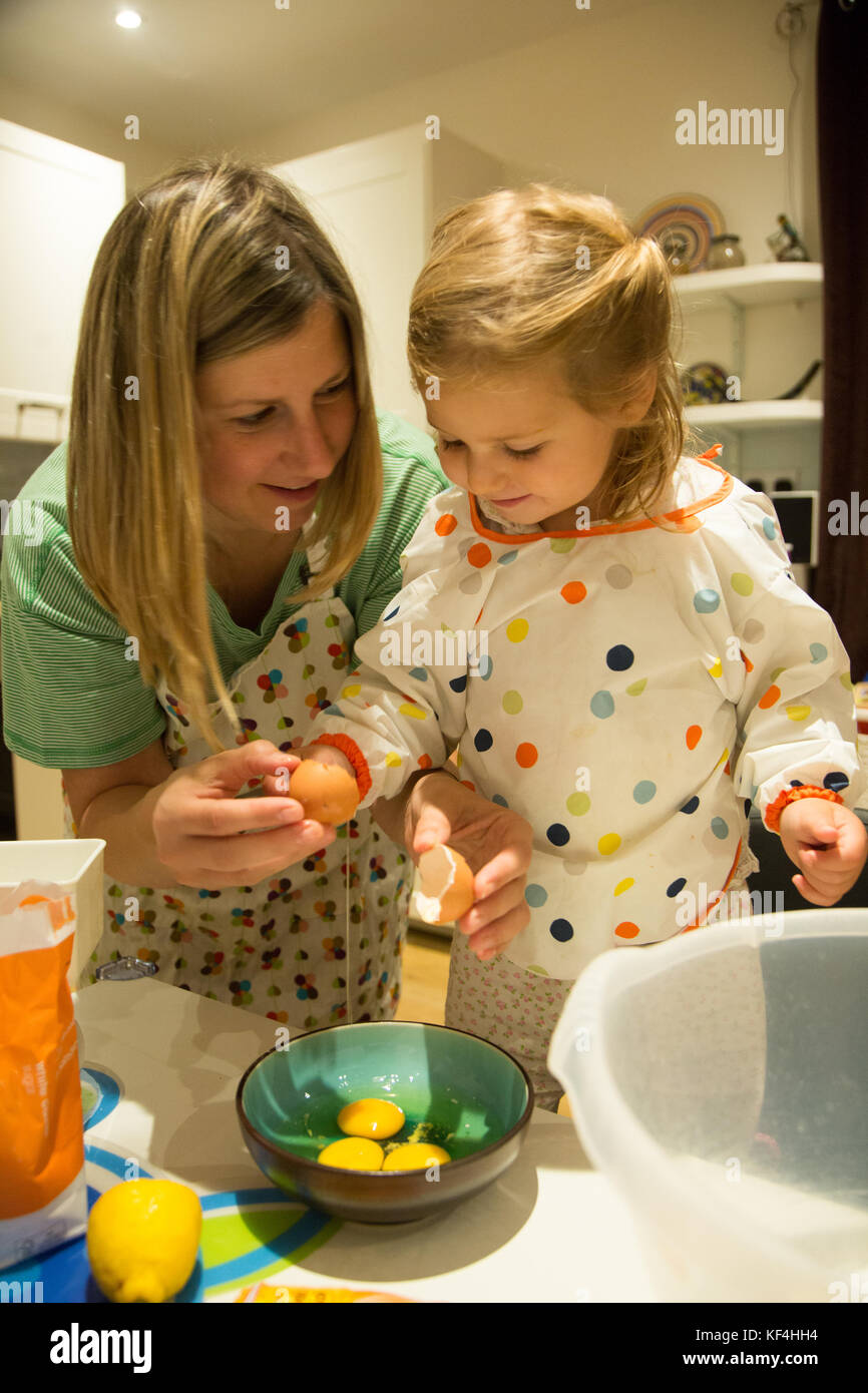 Mother and daughter mixing ingredients in preparation for baking a cake ...