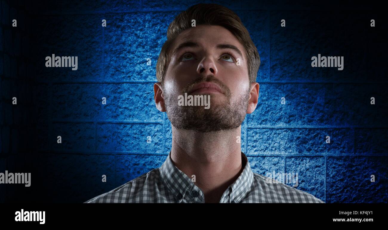 Digital composite of Man looking up with dark blue wall background ...