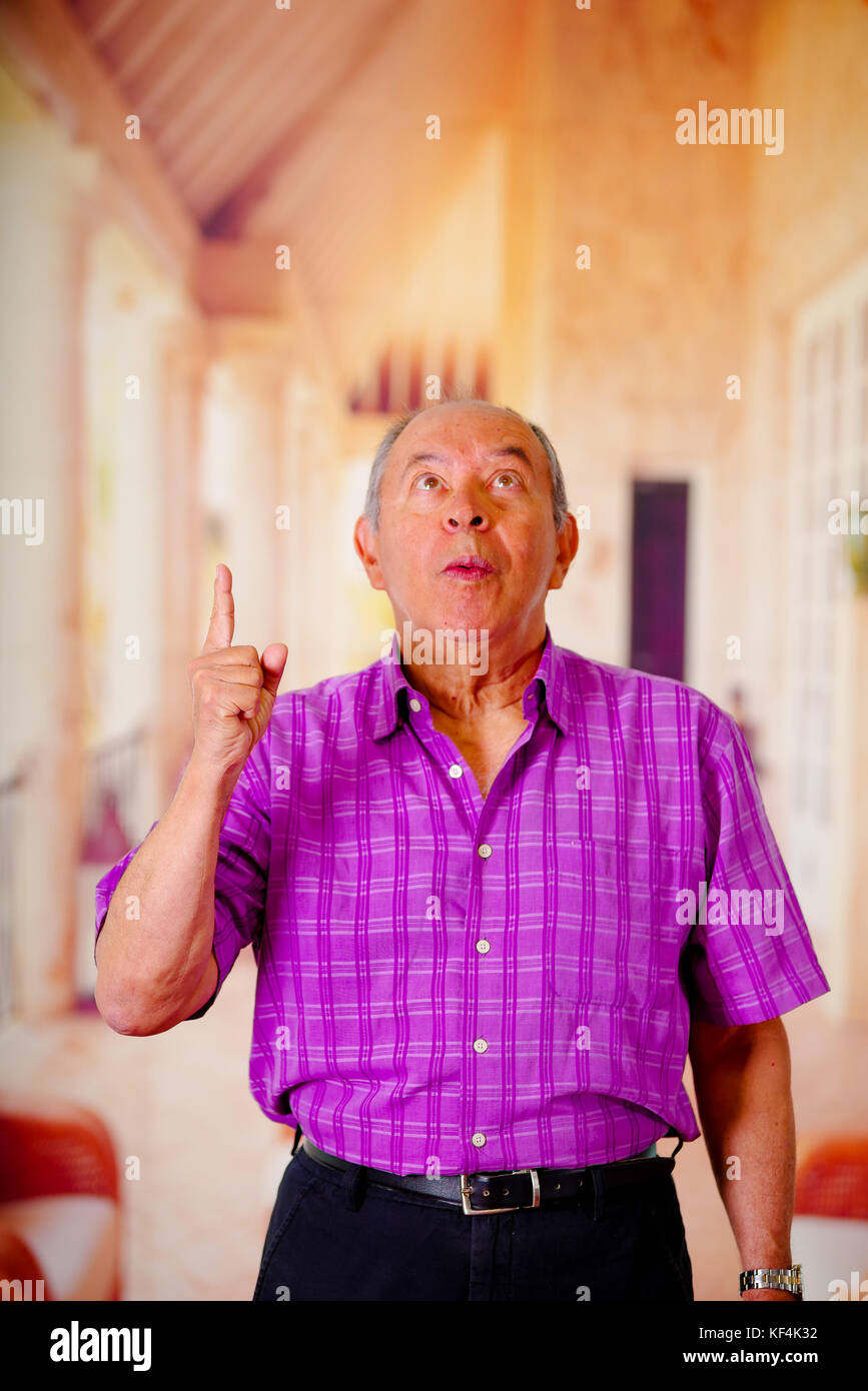 Close up of a happy old man, pointing with his hand to up and wearing a ...