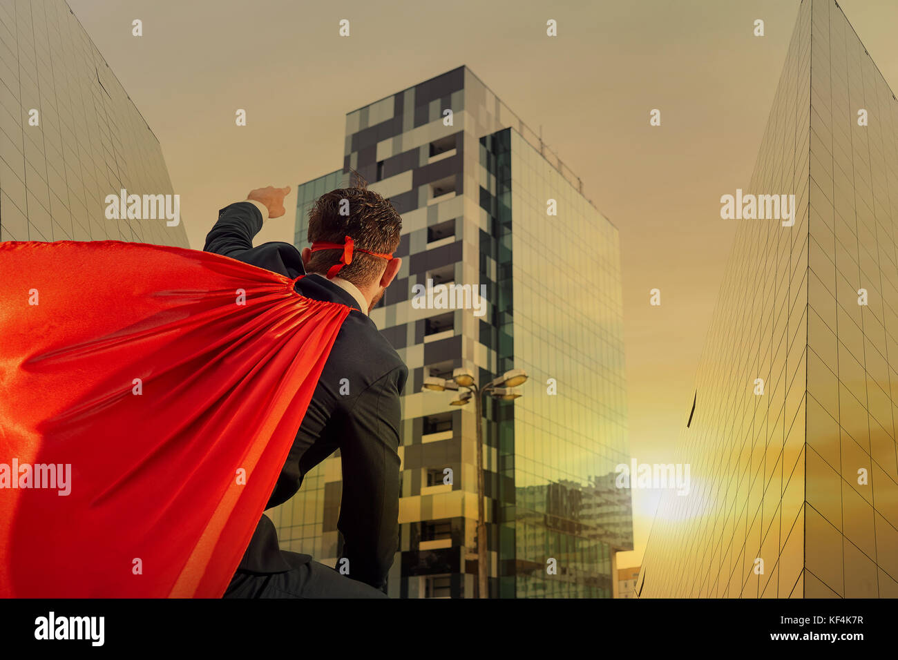 A businessman is a superhero on a business building background o Stock ...