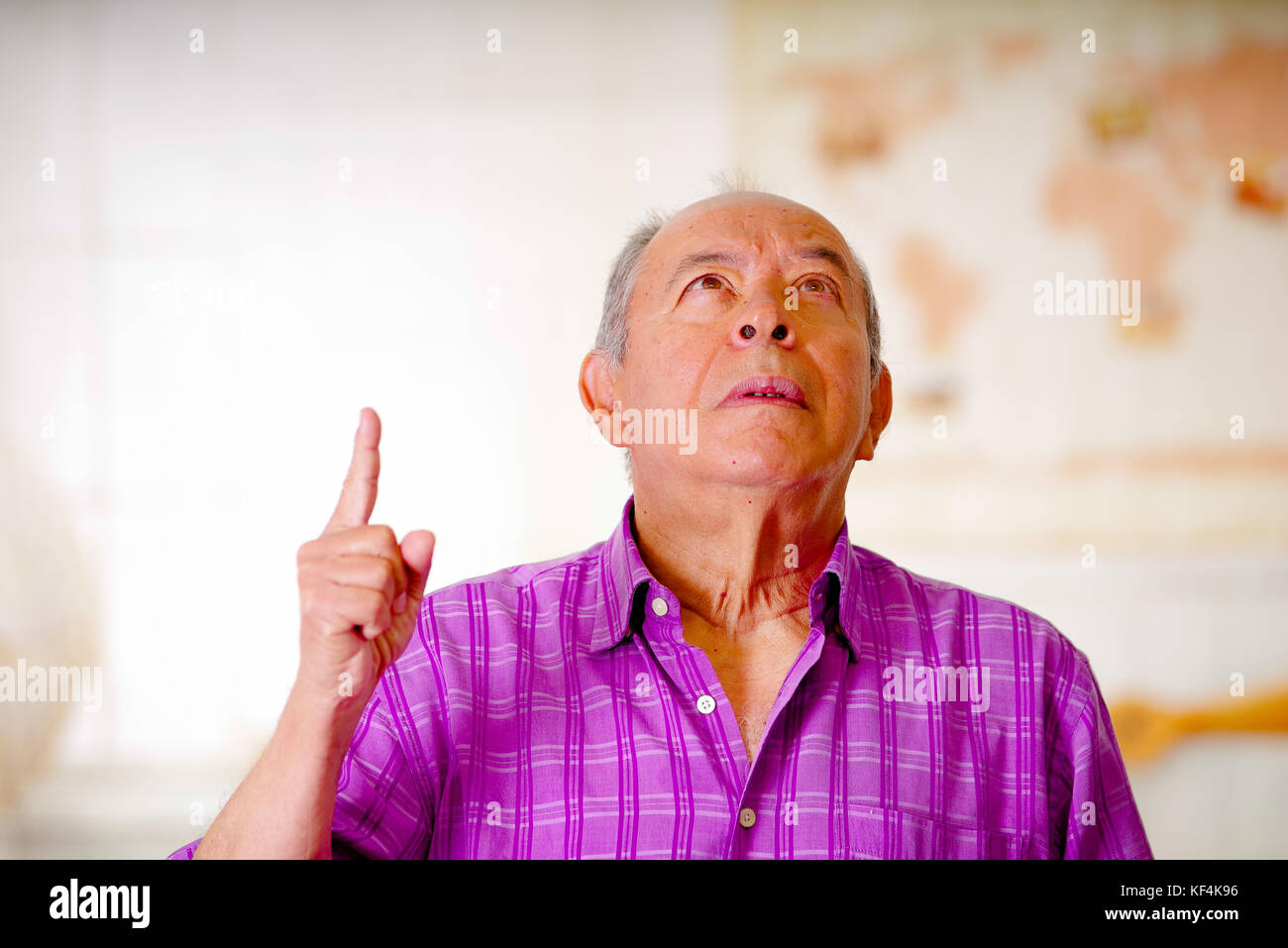Portrait of a happy old man, pointing with his hand to up and wearing a ...