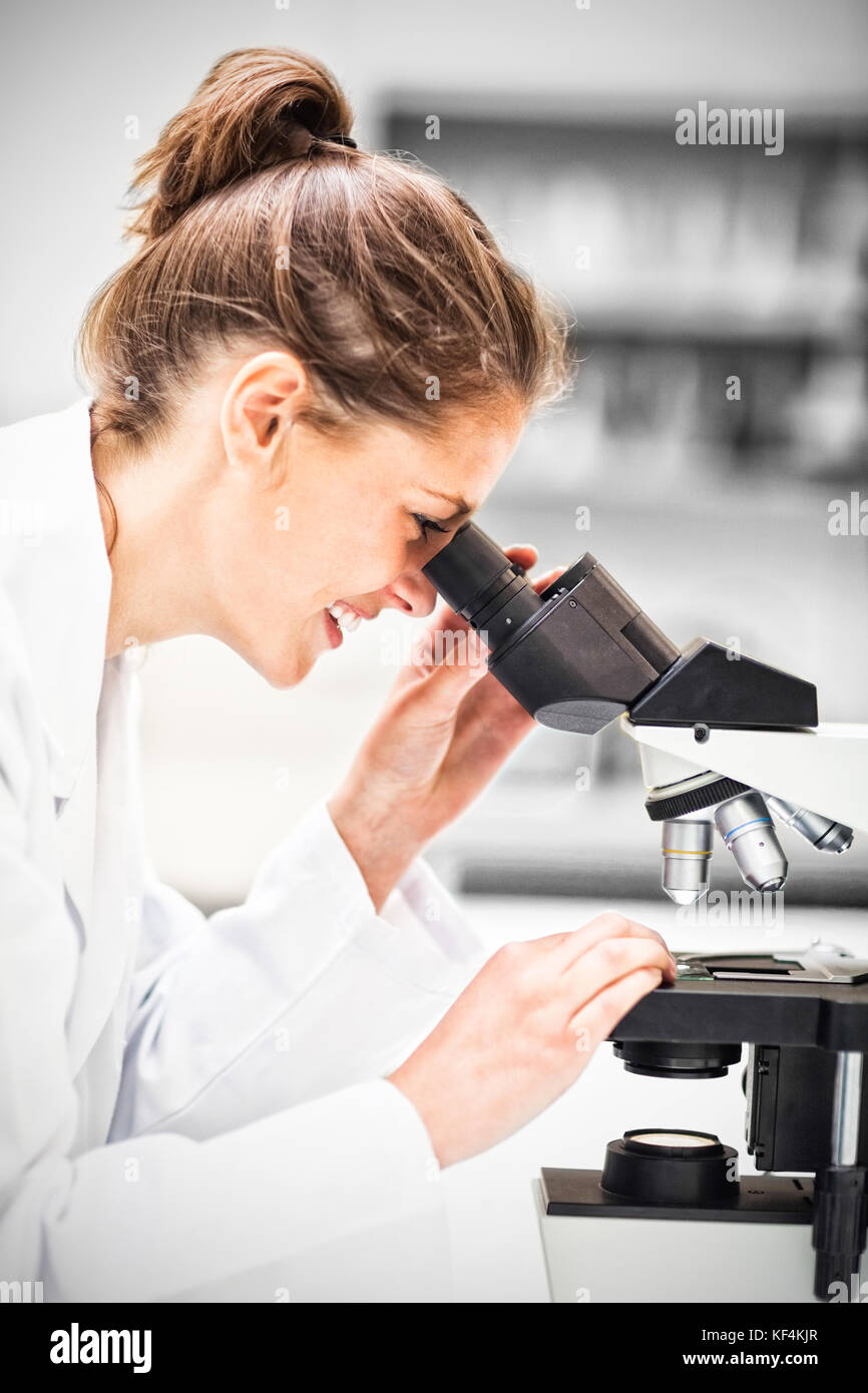 Scientist working on microscope and smiling Stock Photo - Alamy