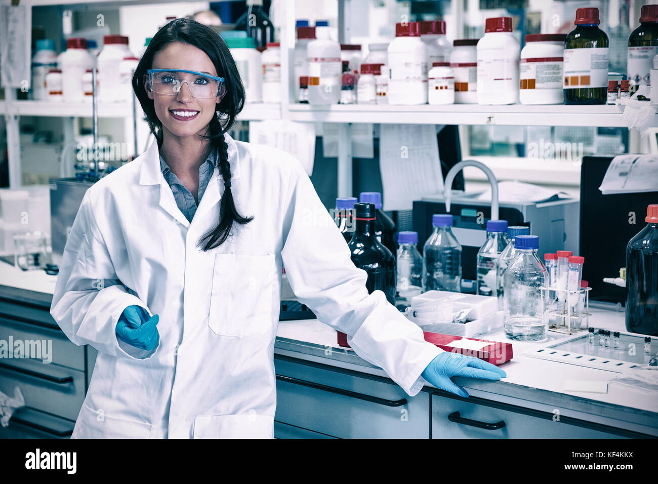 Portrait of a smiling chemist leaning against desk in the laboratory ...